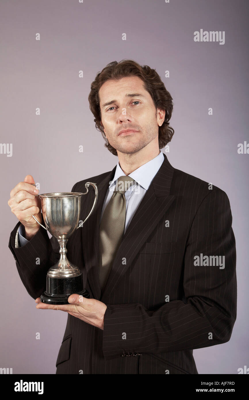 Businessman holding trophy, portrait Stock Photo - Alamy