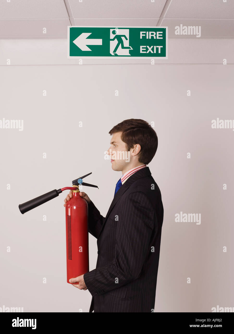 Businessman holding fire extinguisher under exit sign Stock Photo - Alamy