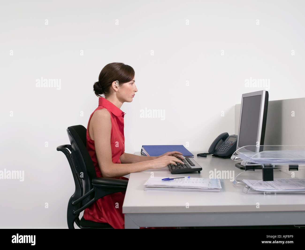 Female office worker using computer at desk in office Stock Photo - Alamy