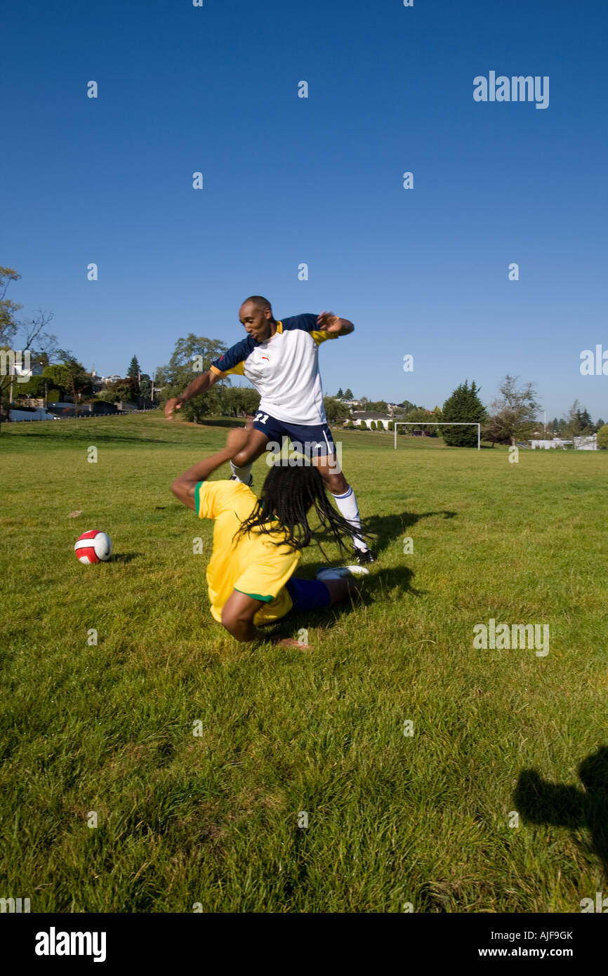 A black African American man playing soccer and slide tackling another ...