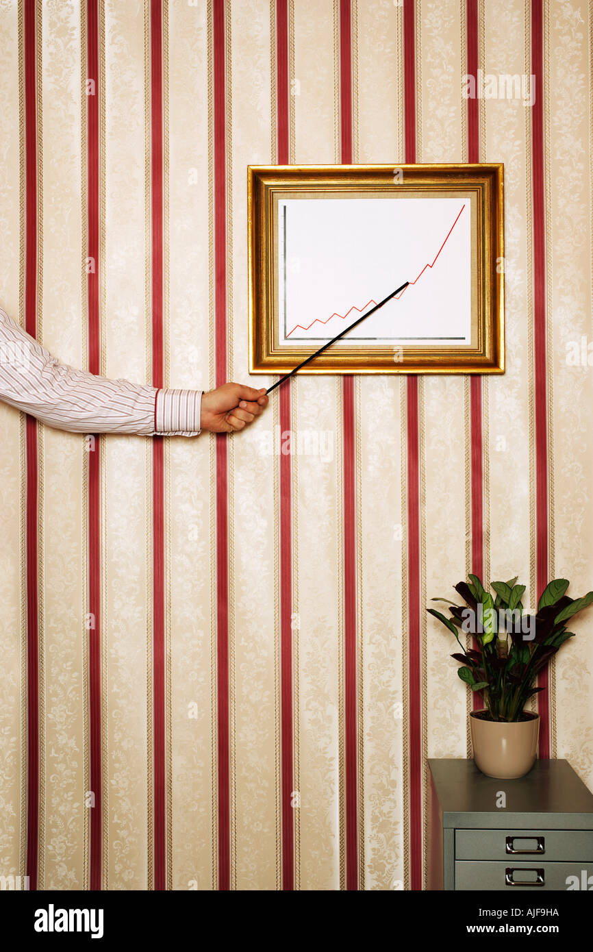Man pointing to framed graph on office wall, close-up of arm and hand ...