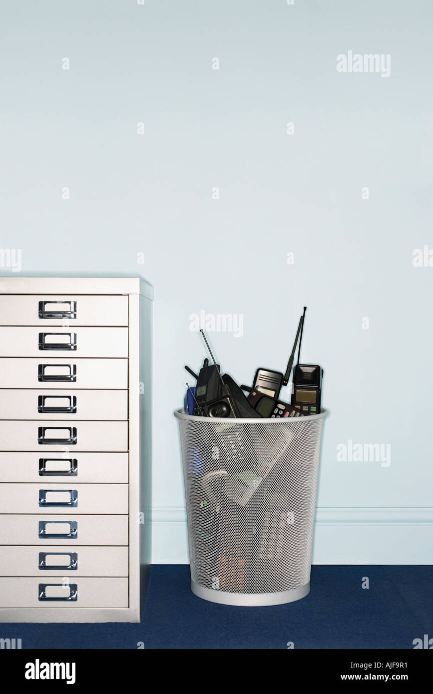 Mobile phones in trash can by filing cabinet Stock Photo - Alamy