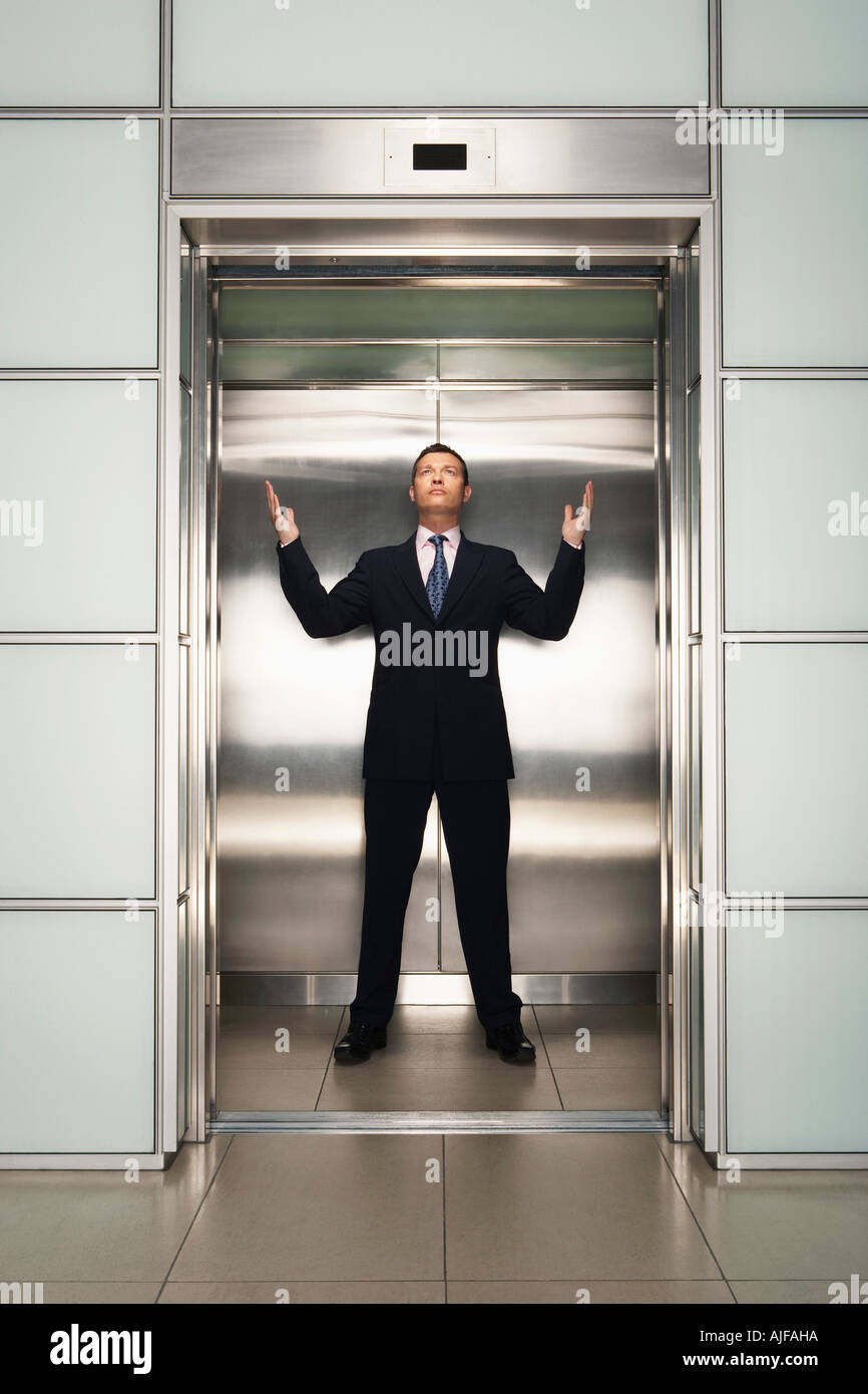 Businessman arms raised in Elevator, front view Stock Photo - Alamy