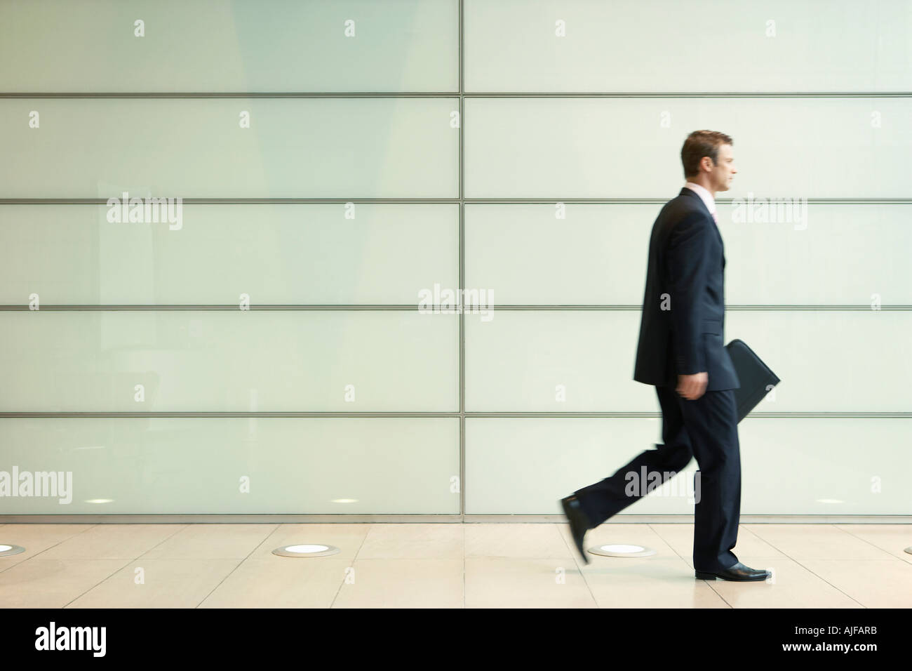 Businessman Striding Down Office Corridor, side view Stock Photo - Alamy