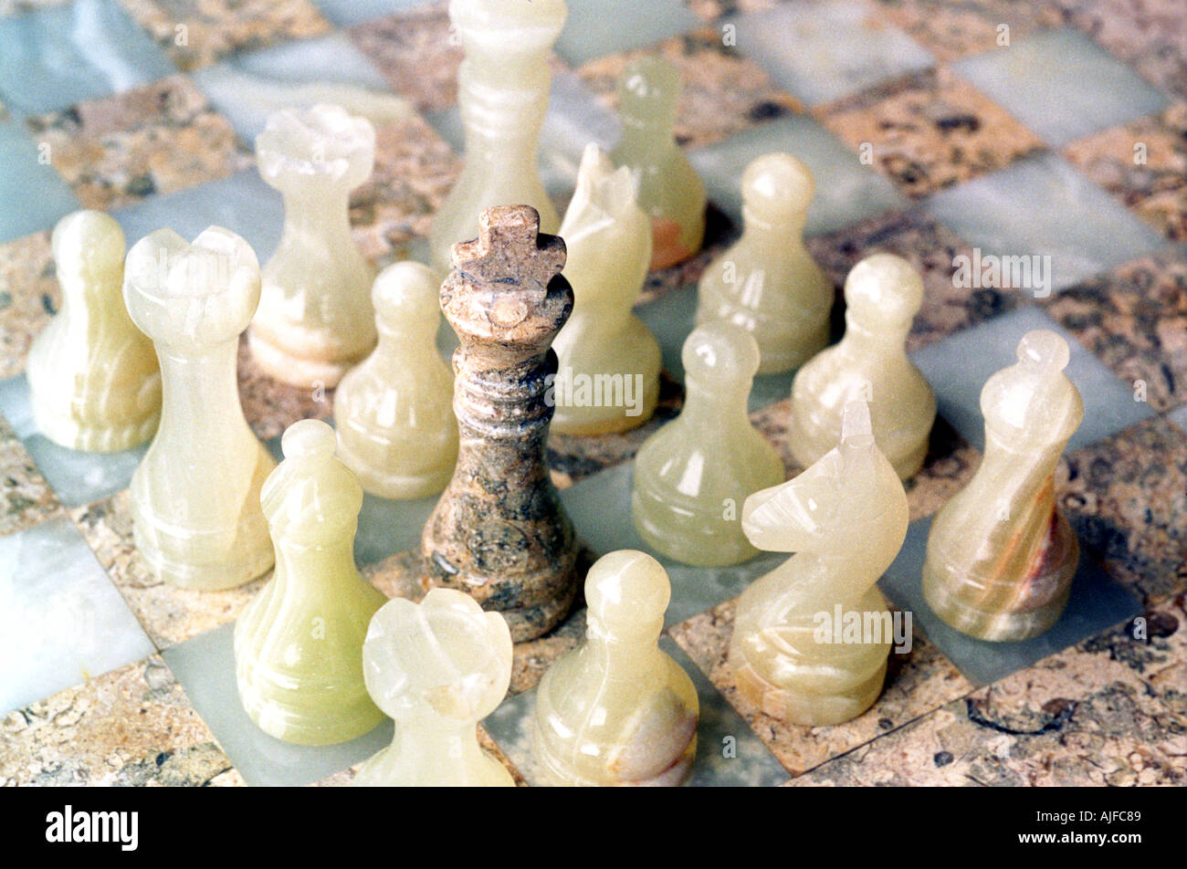 Black king surrounded by white chess pieces Stock Photo - Alamy
