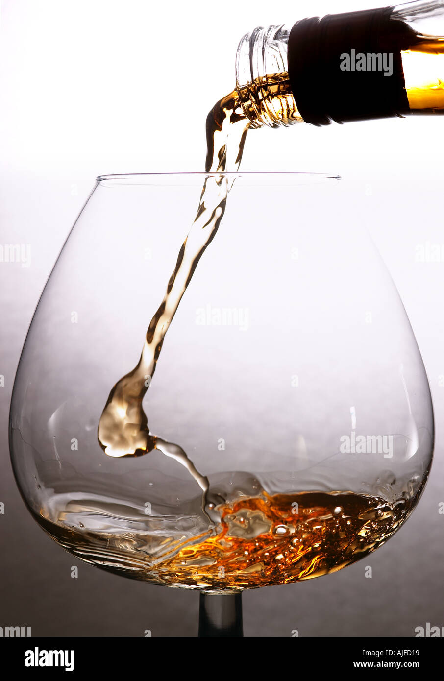 Brandy pouring into glass frozen with flash Stock Photo - Alamy