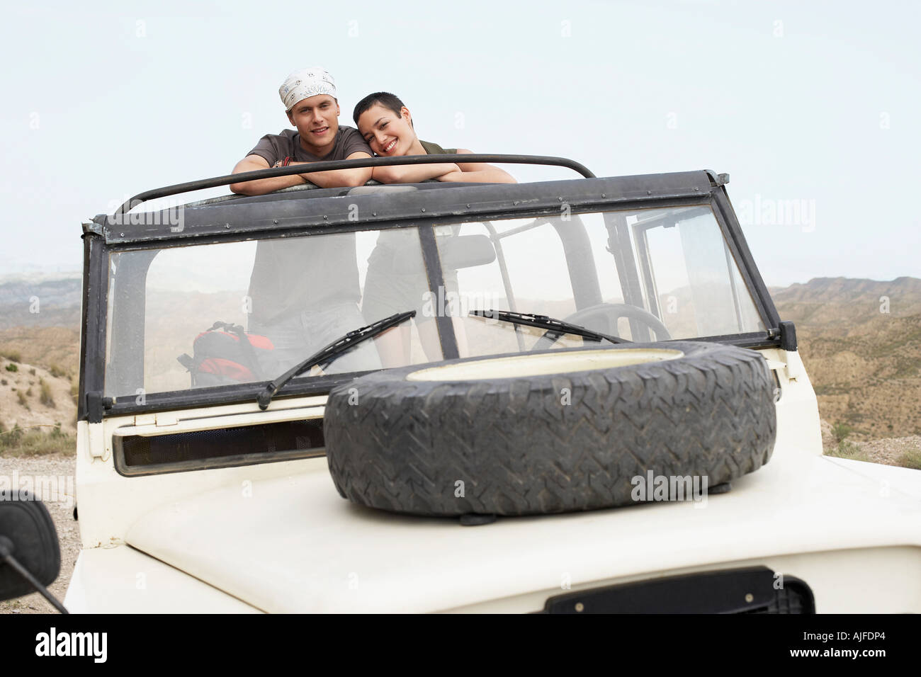 Couple standing side by side in stationary four wheel drive car in ...