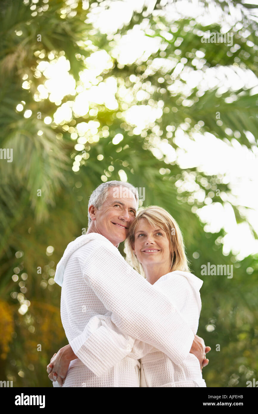 Middle-aged couple standing by palm trees hugging, portrait Stock Photo ...