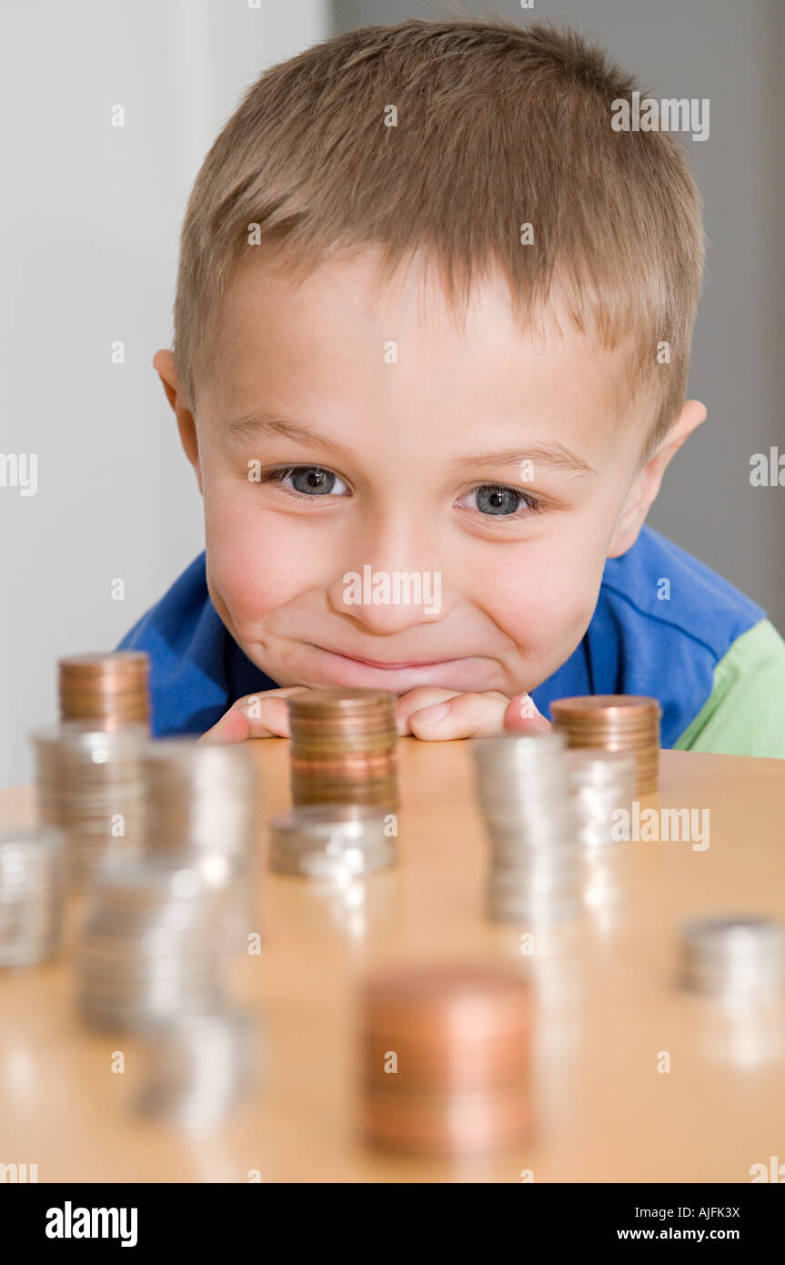 Boy looking at stacks of coins Stock Photo - Alamy