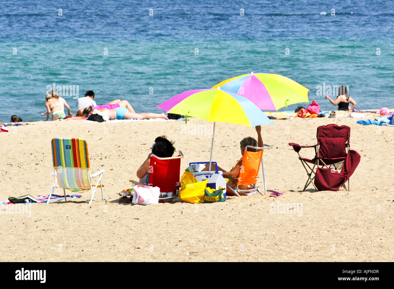 People on the beach shading themselves with colorful umbrellas in ...