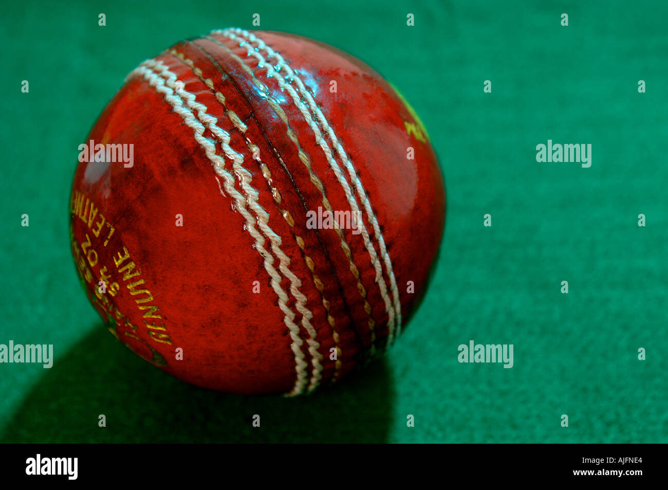 a real leather cricket ball on a green background Stock Photo - Alamy