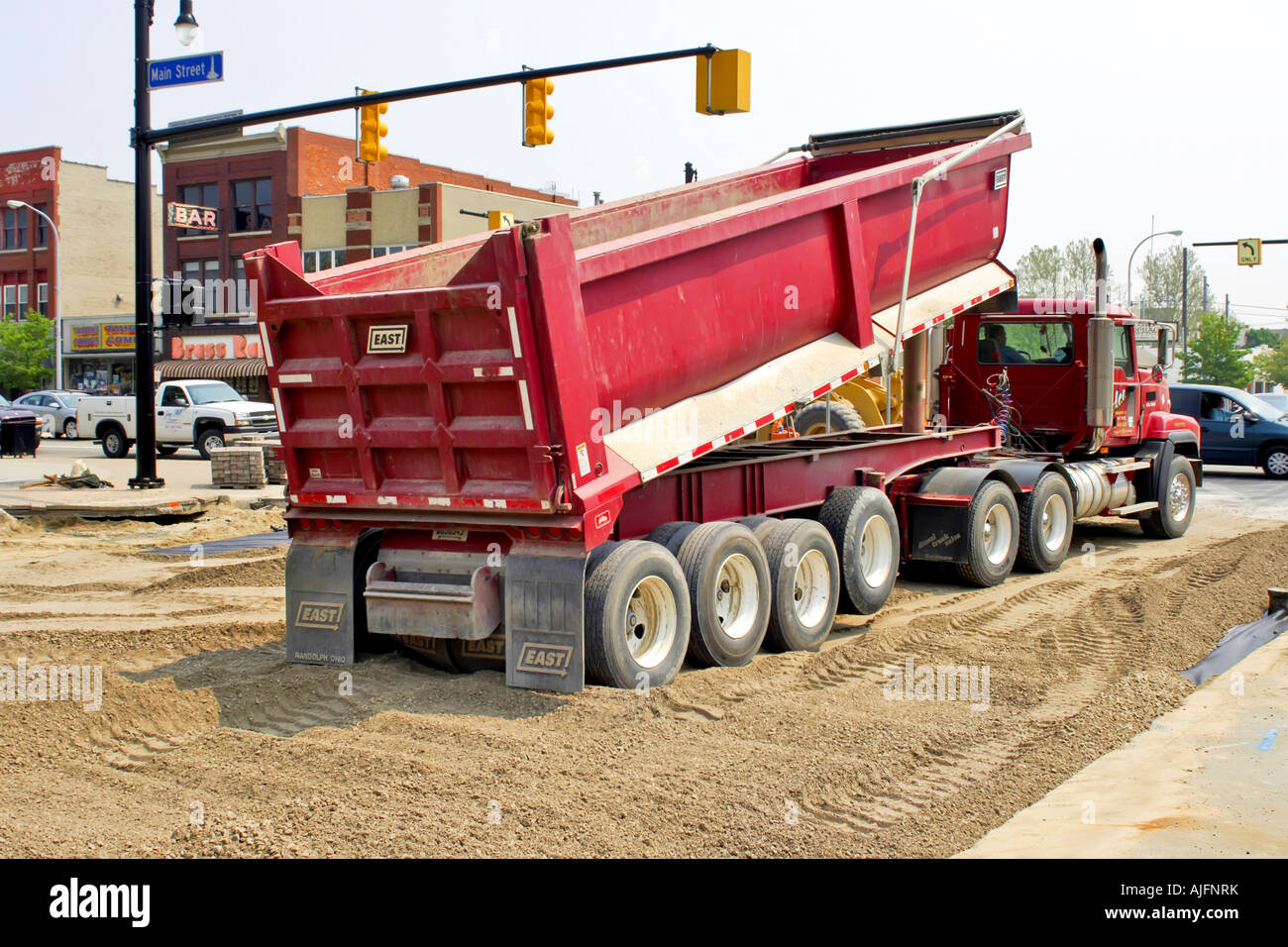 A large tipper truck unloads sand at a repaving project in downtown ...
