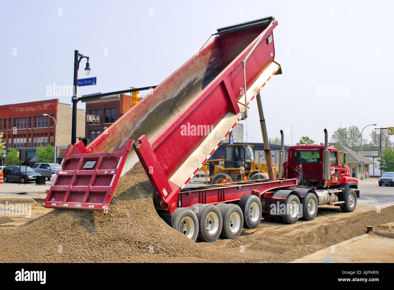 A large tipper truck unloads sand at a repaving project in downtown ...