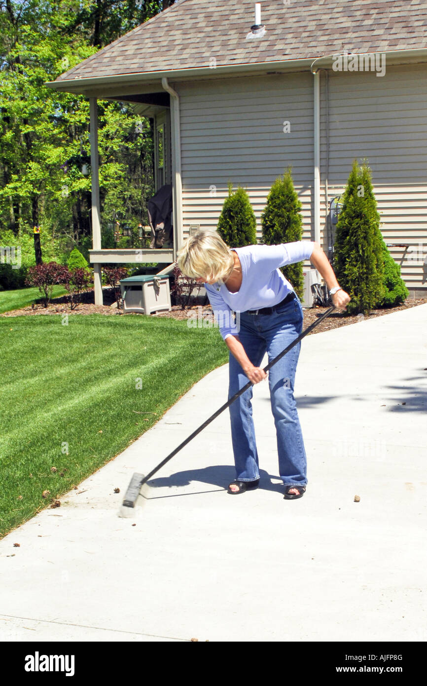 Attractive female sweeping the driveway clean outside her home Stock ...