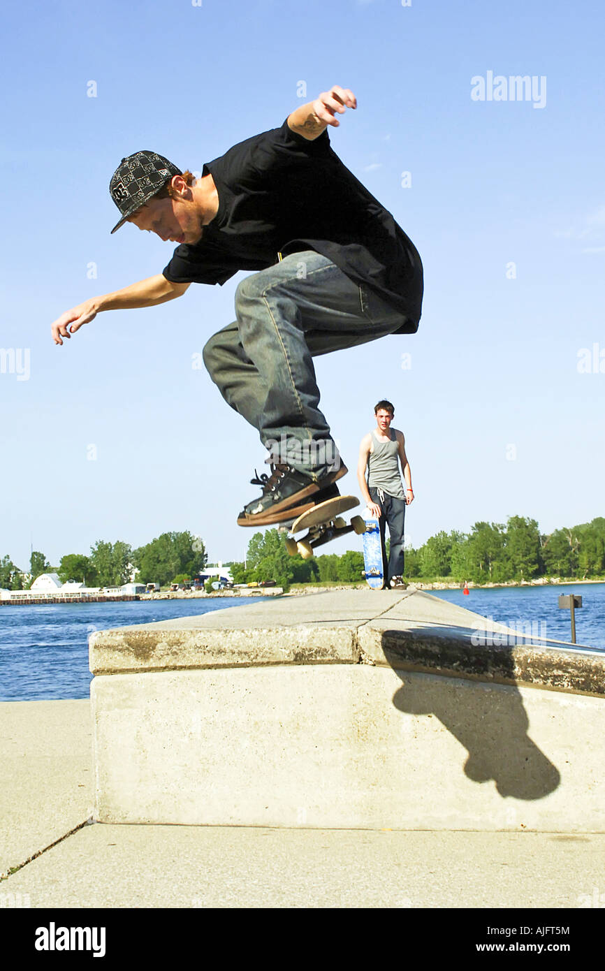 Teenage male practices jumps tricks and maneouvers on a skateboard ...