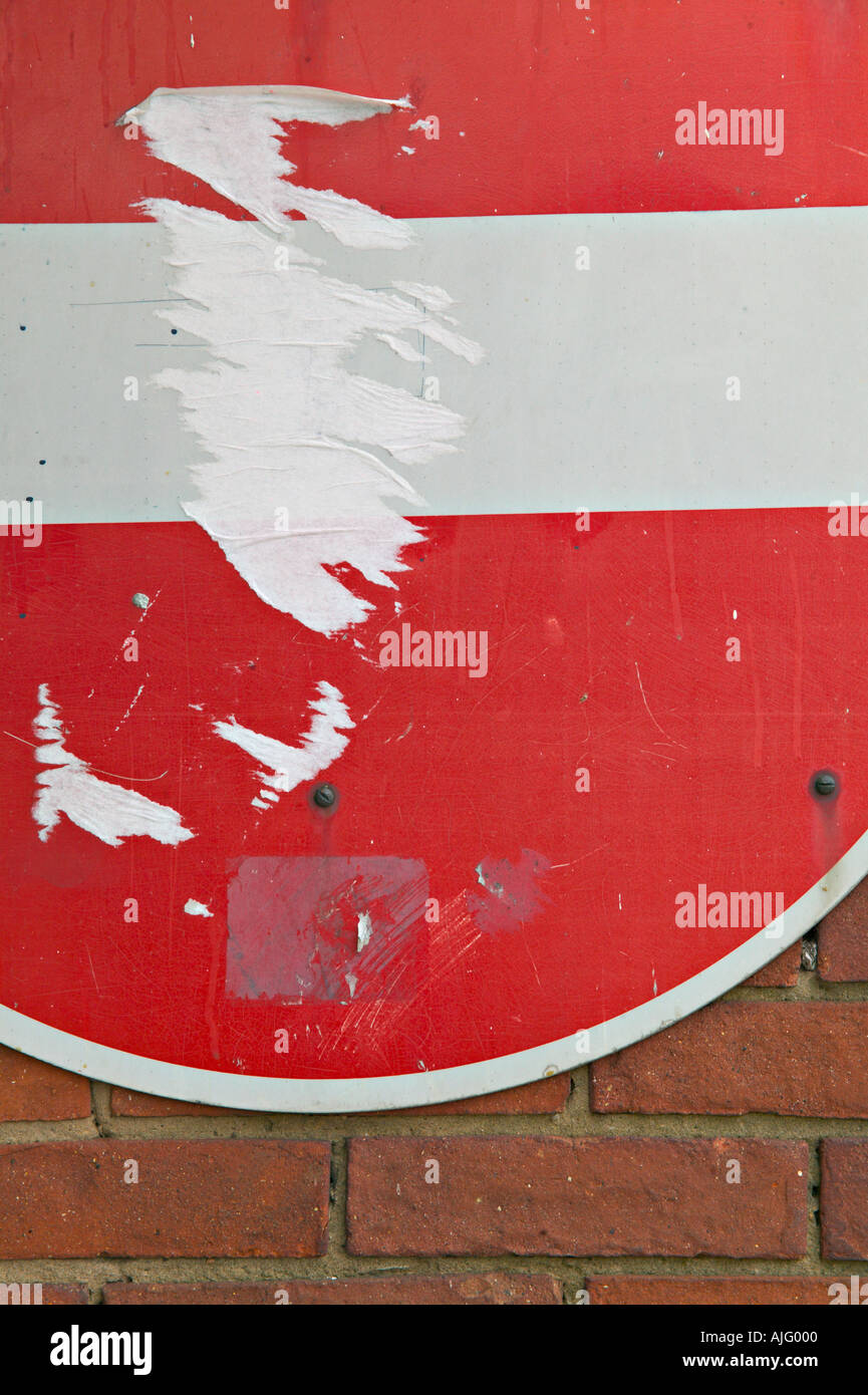 No entry sign with torn off poster affixed to a brick wall at Derby bus ...