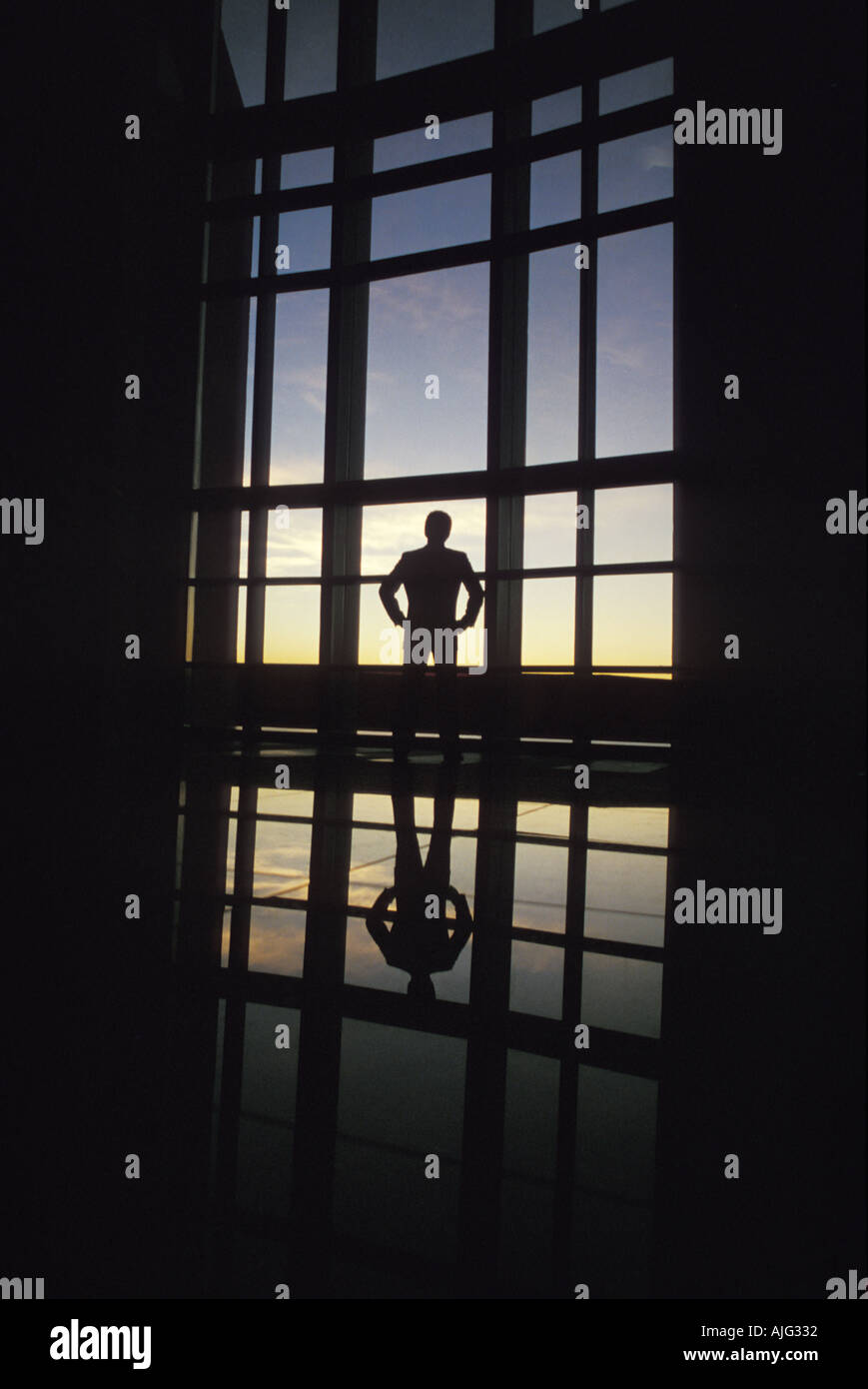 Silhouetted man gazing out big lobby window Stock Photo - Alamy