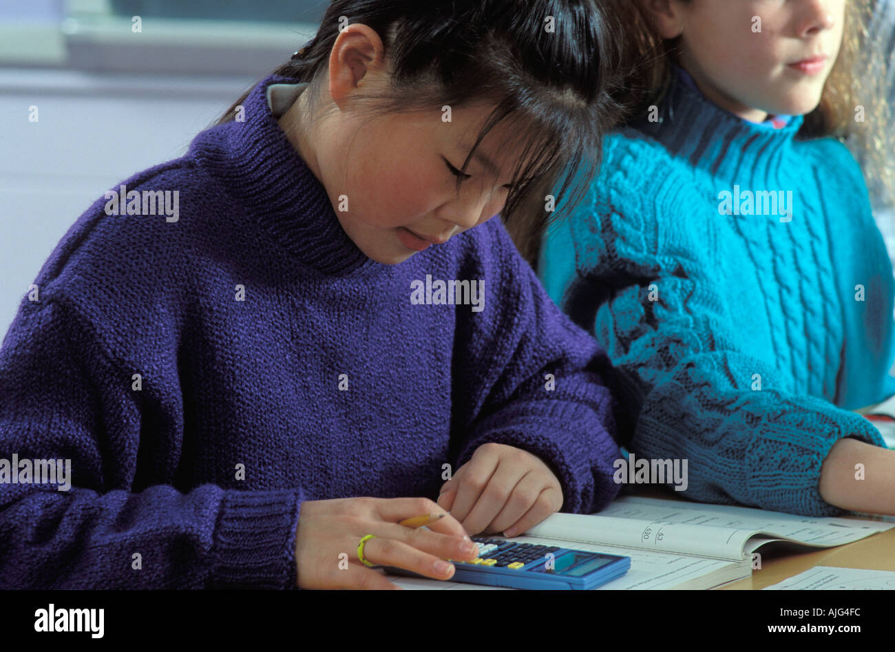 Asian American female student using calculator to do math work in class ...