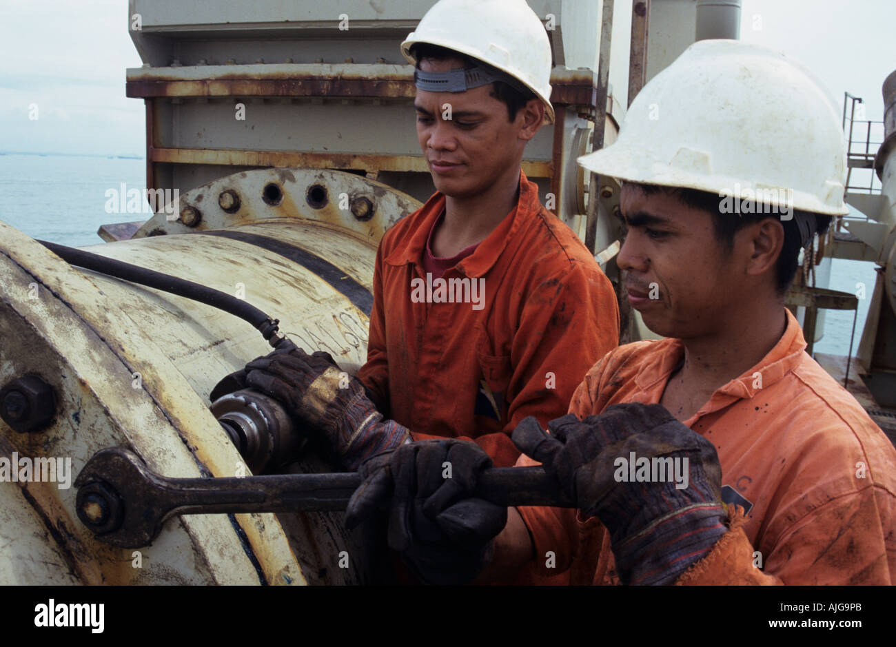 Philippino crewmen tightening bolts on ship during maintenance, Malacca ...