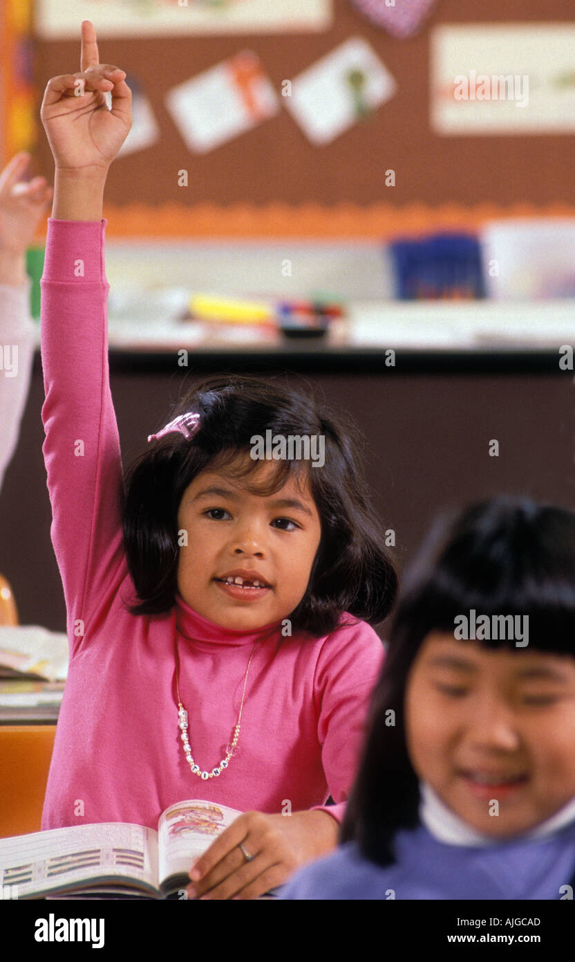 Latino female student raising hand in elementary school class Stock ...