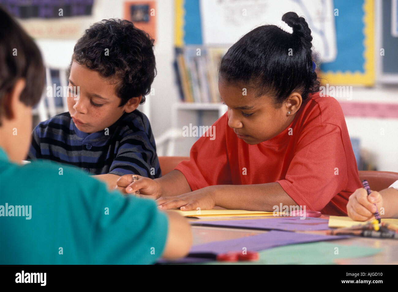 Latino African American students Drawing with crayons at desk in ...