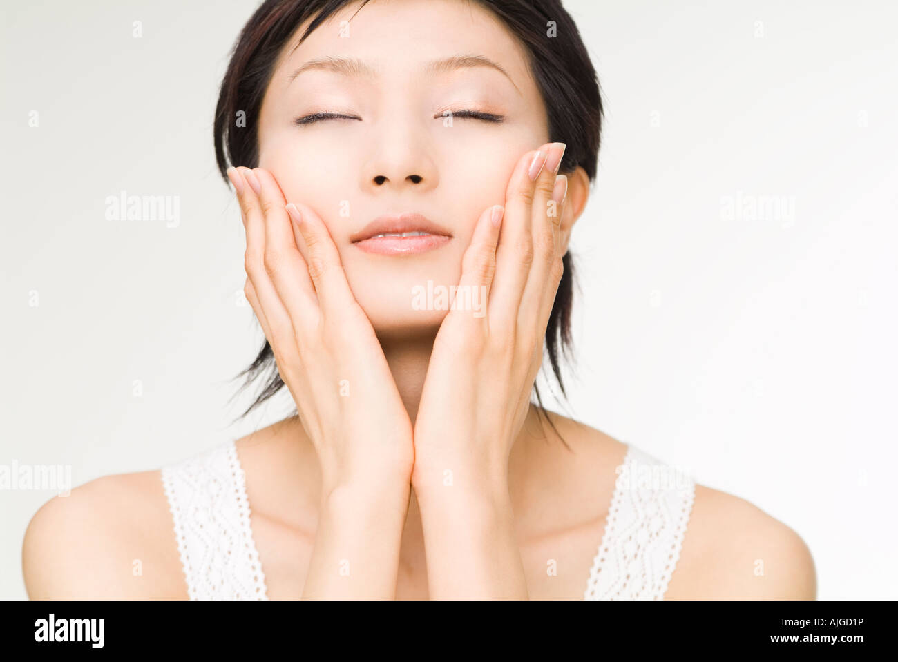 Young woman touching her cheeks Stock Photo - Alamy