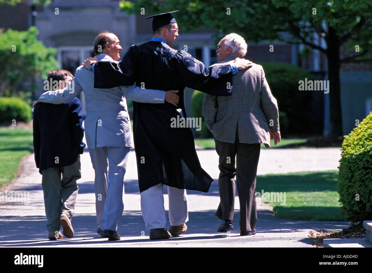 Caucasian male graduate walking with Dad Grandfather and brother on ...