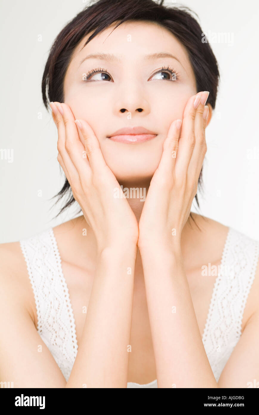 Young woman touching her cheeks Stock Photo - Alamy