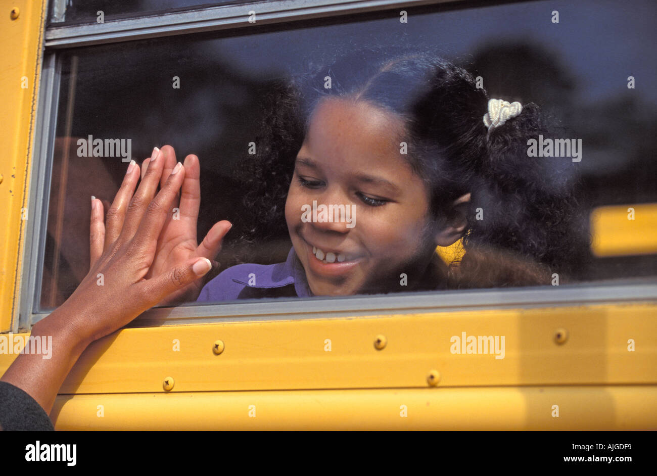 African-American Child looking through the window of the school bus as ...