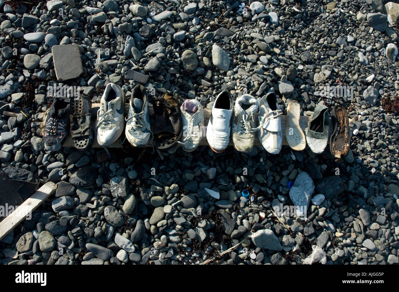 Shoes and trainers washed up on beach in a line Stock Photo - Alamy
