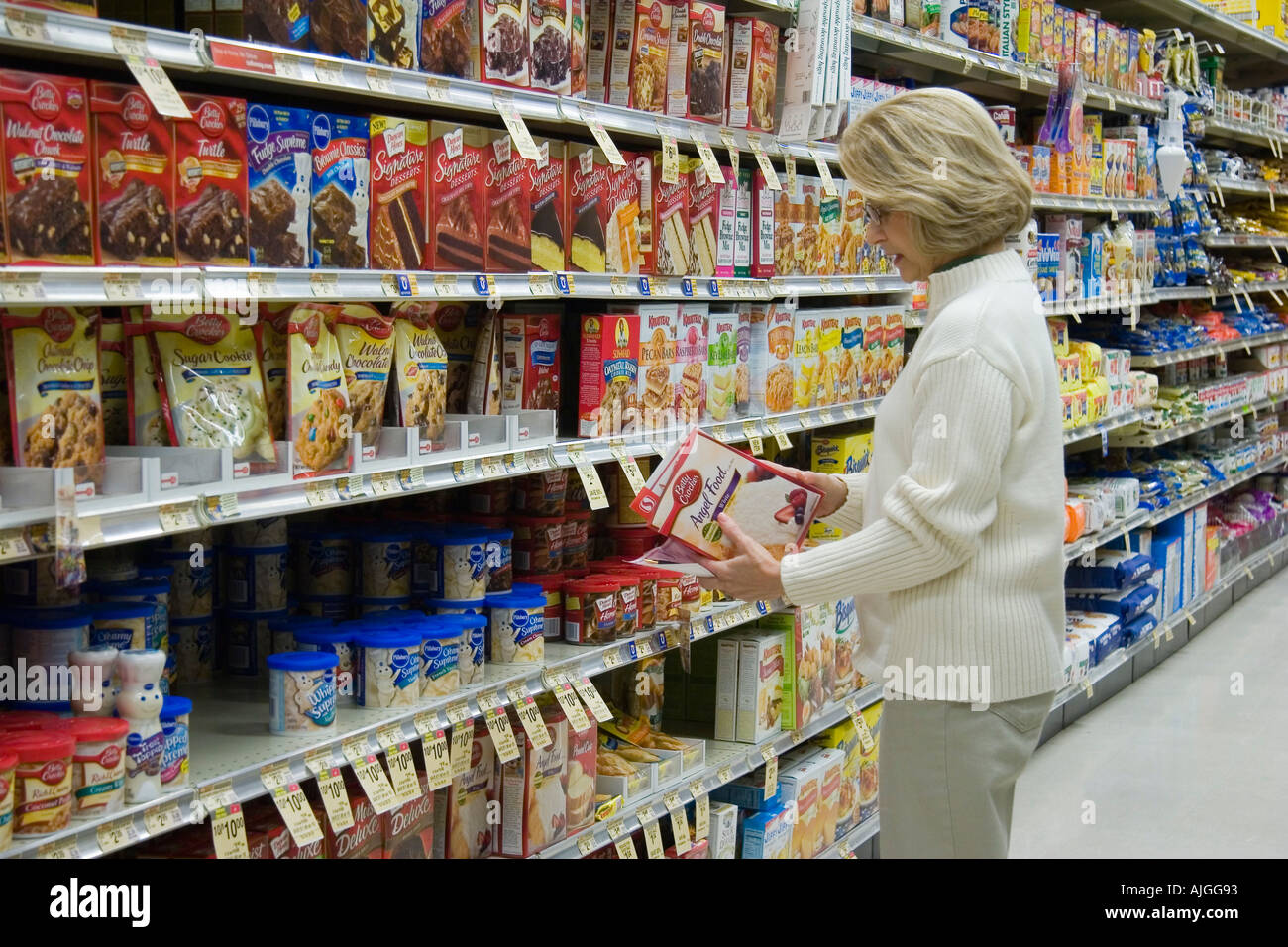 Woman doing comparison shopping at grocery store Stock Photo - Alamy