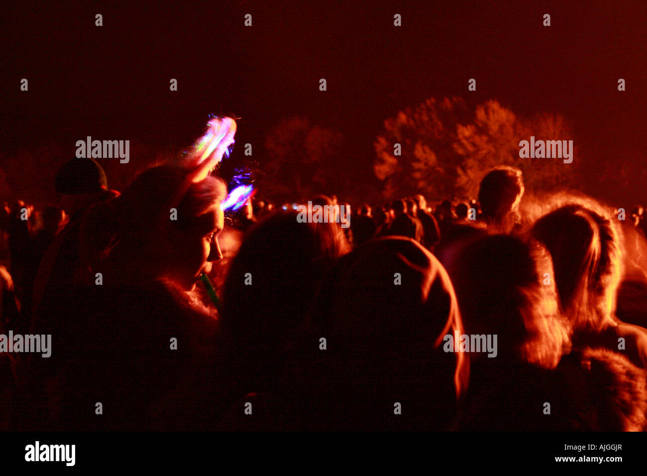 Young woman with novelty ears among crowd lit by light from bonfire at ...