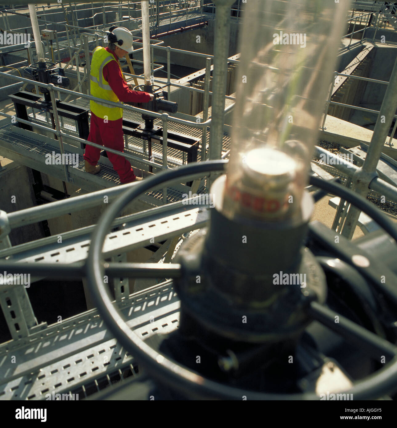 Operator controlling water flow at sewage treatment plant, England, UK ...