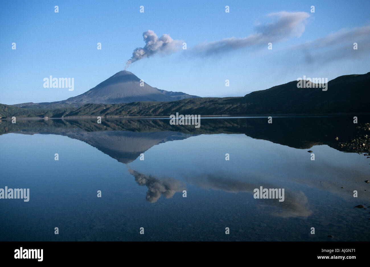 Karymsky volcano erupting and reflected in lake Kamchatka Russia Stock ...