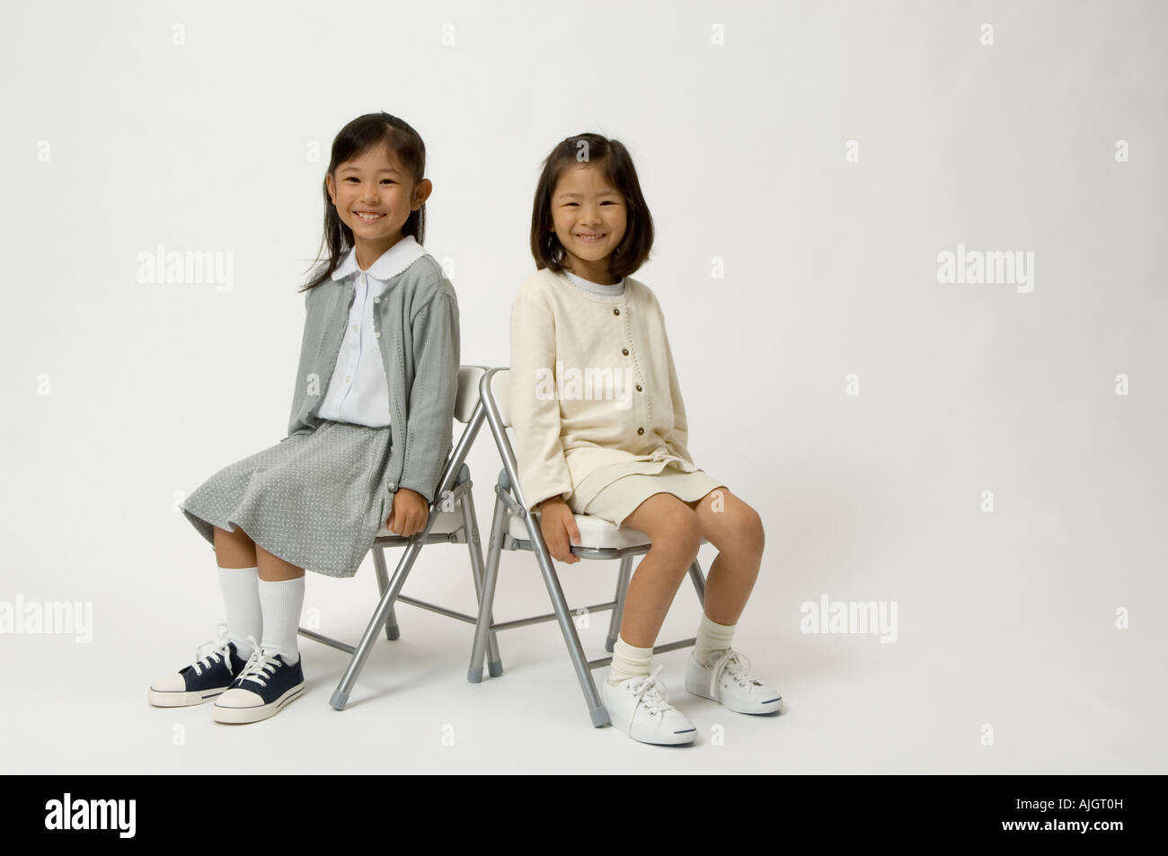 Two girls sitting on chairs hi-res stock photography and images - Alamy