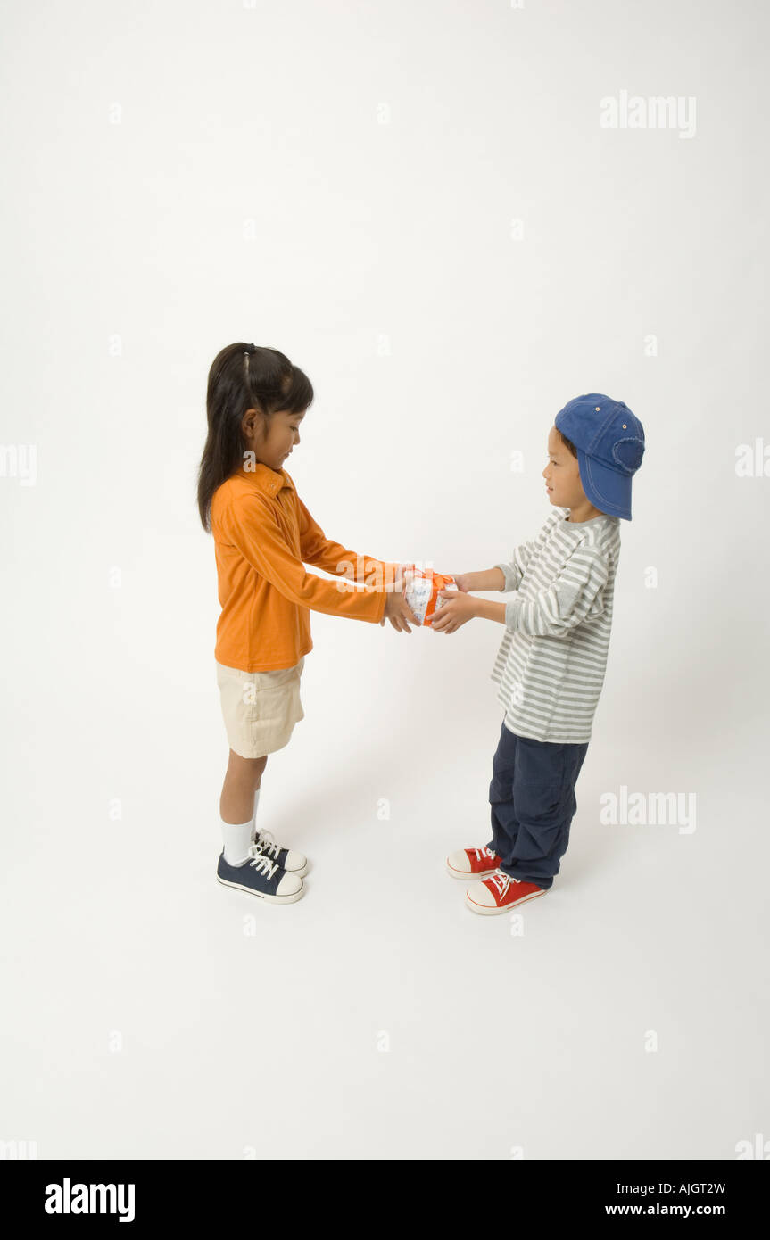 Elementary age child giving gift to friend Stock Photo - Alamy