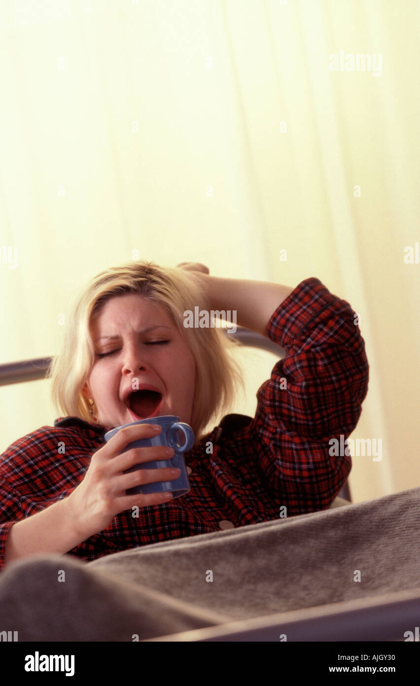 Groggy woman yawning drinking coffee in bed Stock Photo - Alamy