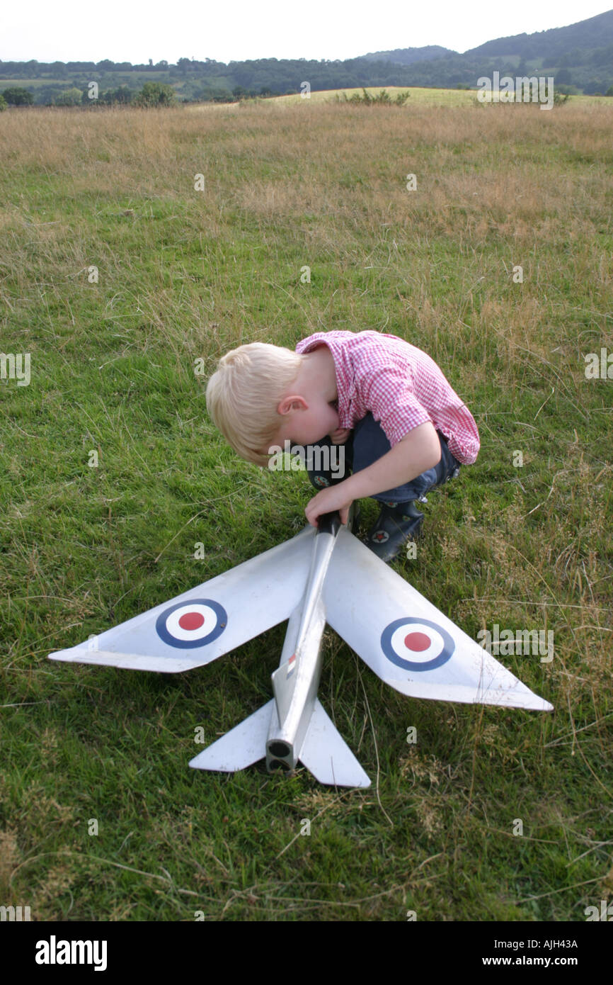 boy aged 3 in field bending over model jet plane Stock Photo - Alamy