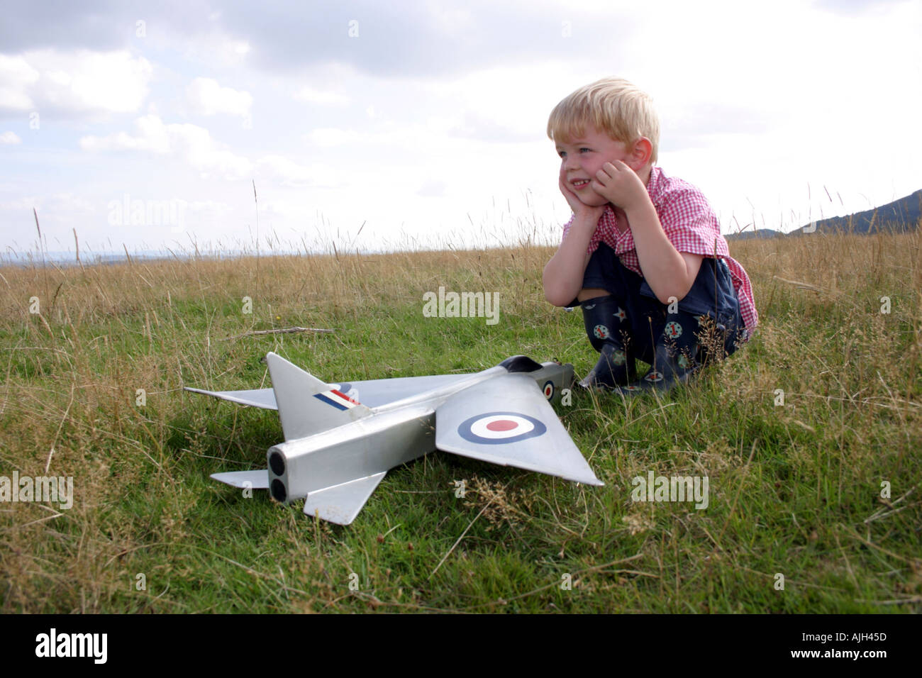 boy 3 in field bending over model jet plane Stock Photo - Alamy