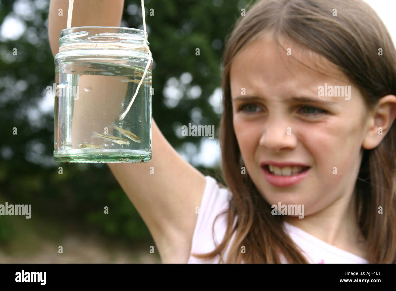 girl 8 looking into jar full of tiddlers caught in a river Stock Photo ...