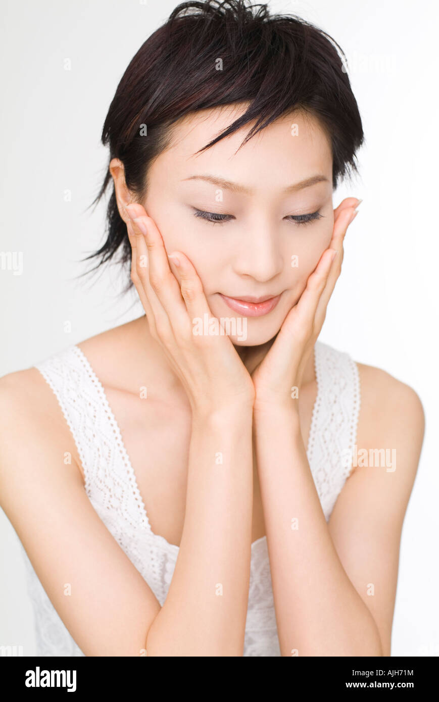 Young woman touching her cheeks Stock Photo - Alamy