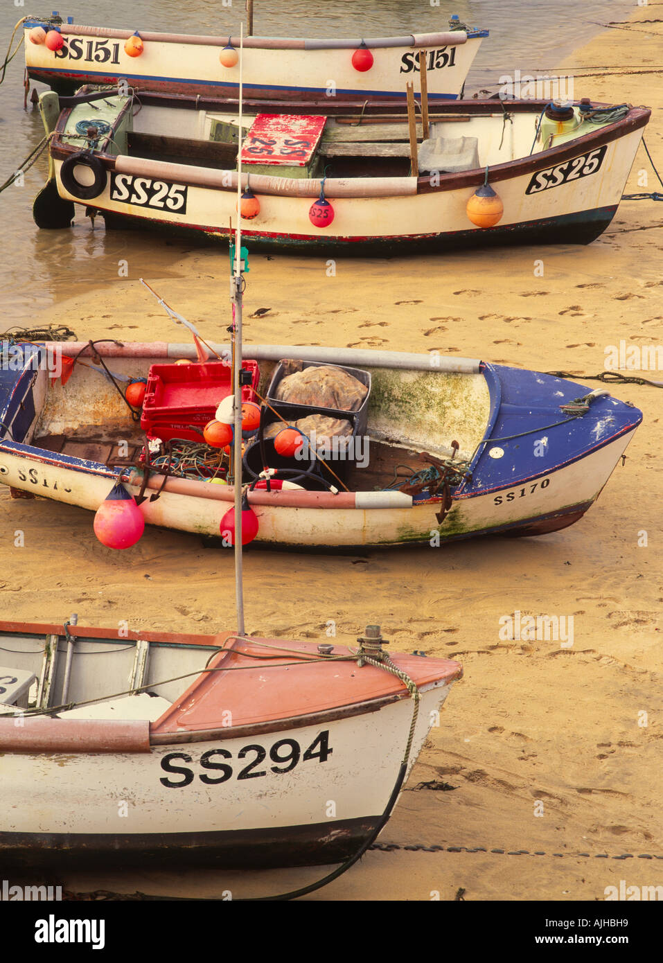 Small fishing boats pulled up on the beach at St. Ives harbour ...