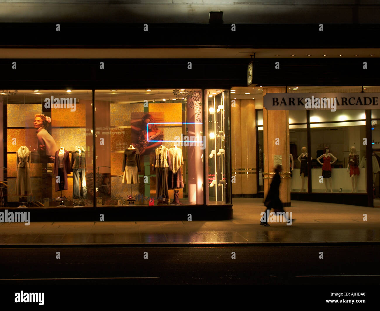 Woman walking alone on rainy night past Barkers Arcade stores on ...
