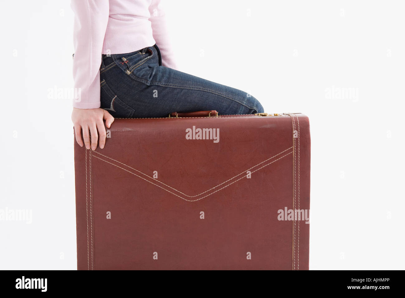 Woman sitting on suitcase Stock Photo - Alamy
