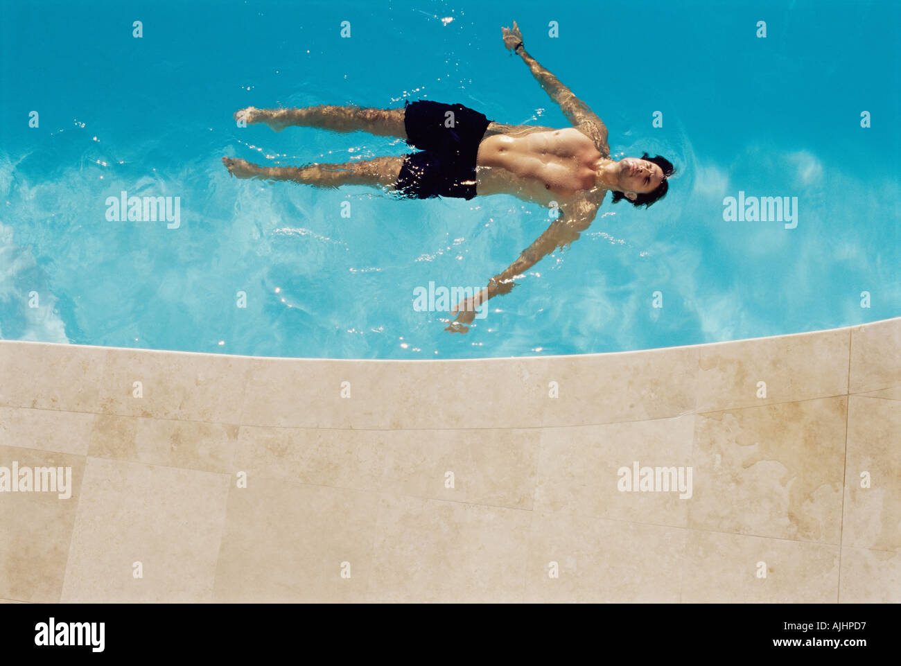 Man floating in swimming pool Stock Photo - Alamy