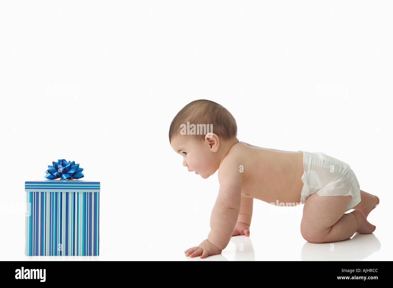 Baby crawling towards gift box Stock Photo - Alamy