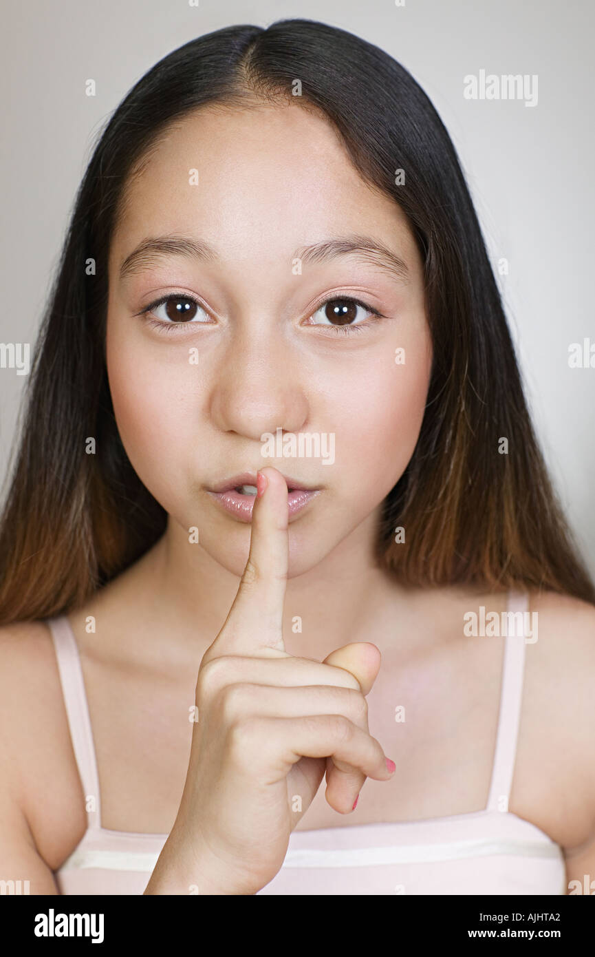Girl putting a finger to her lips Stock Photo - Alamy