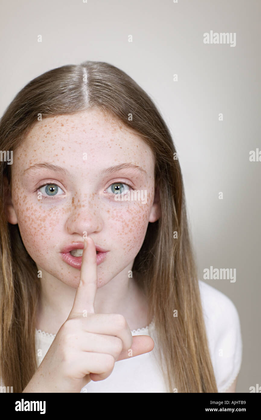 Girl putting a finger to her lips Stock Photo - Alamy