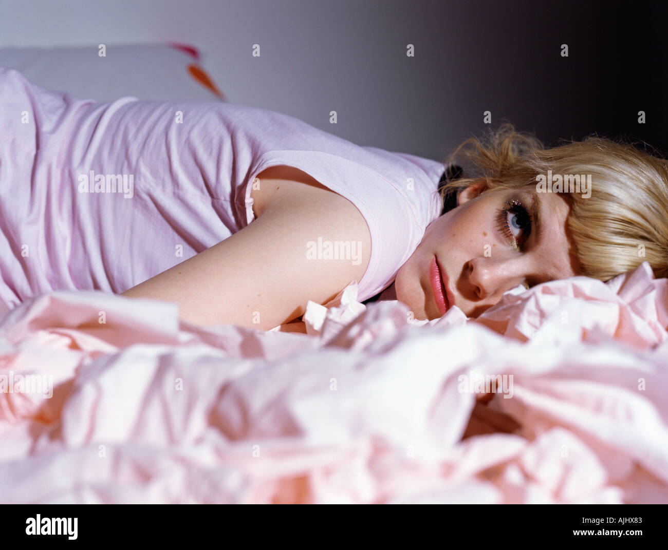Woman lying on bed looking sad Stock Photo - Alamy