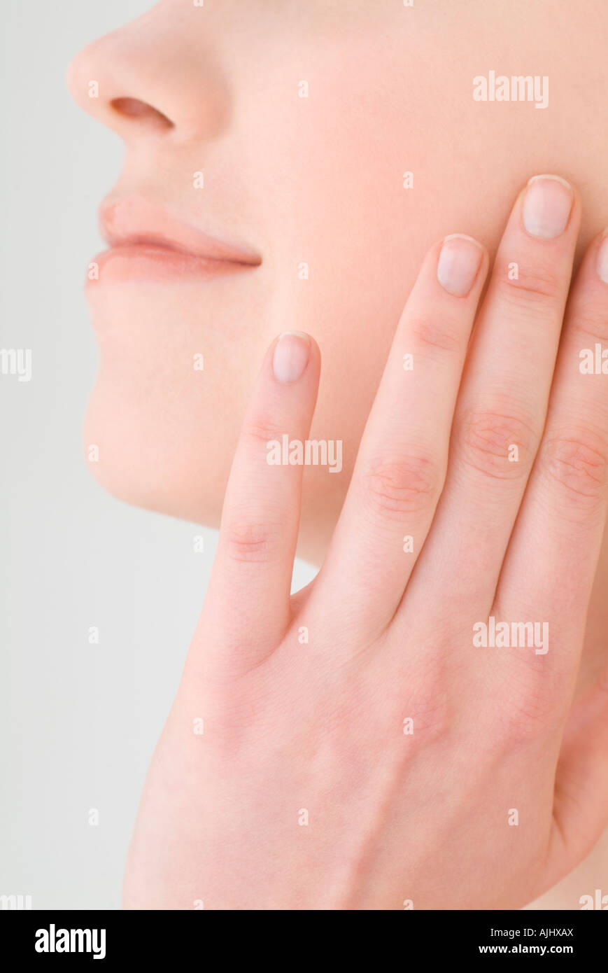 Young woman touching her cheek, close-up Stock Photo - Alamy